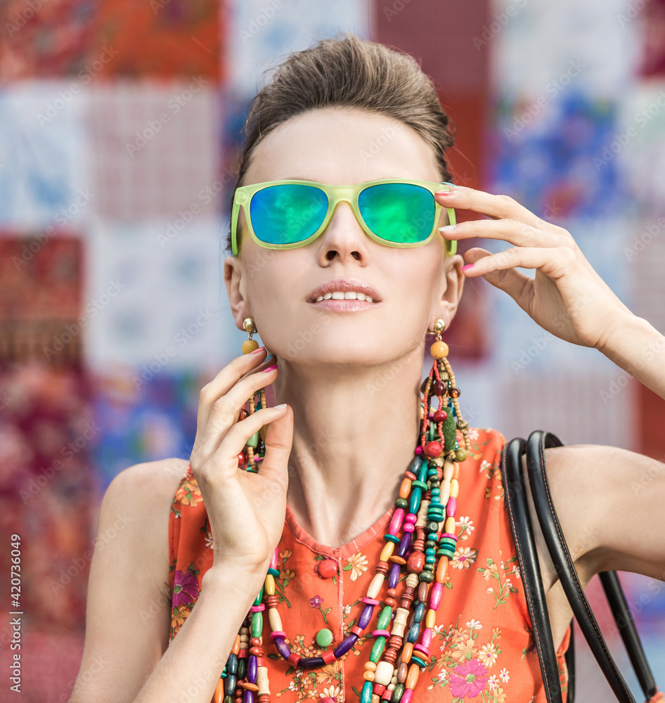 Beautiful woman wearing bright colorful outfit and holding bag over ...