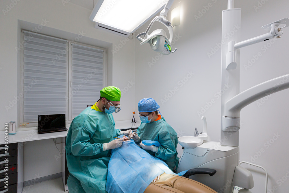 Foto de Team of dental surgeons performs surgery on teeth. in a modern ...