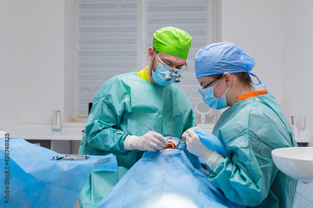 Team of dental surgeons performs surgery on teeth. in a modern clinic ...