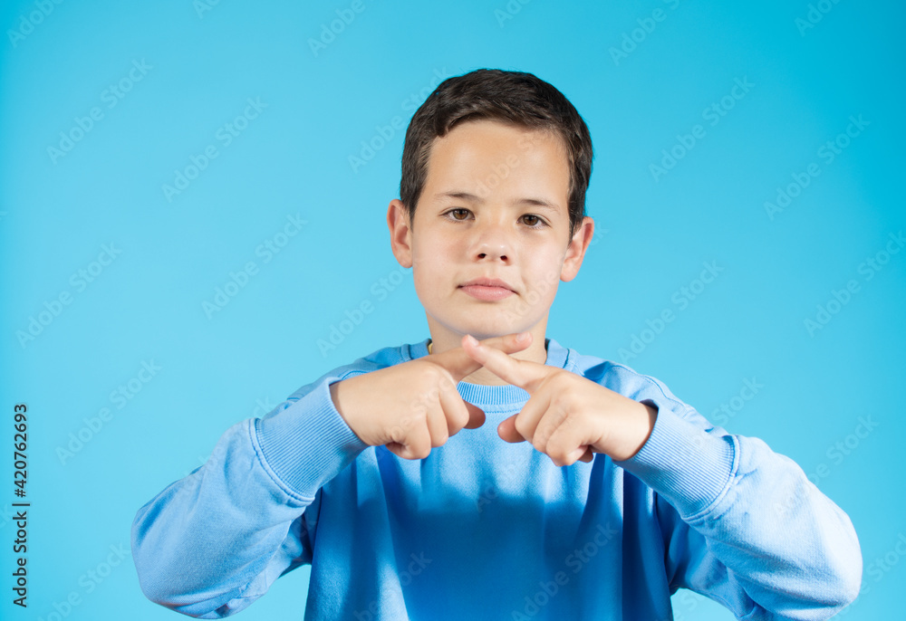 Cute Caucasian kid boy wearing casual sweater against blue wall. Angry ...