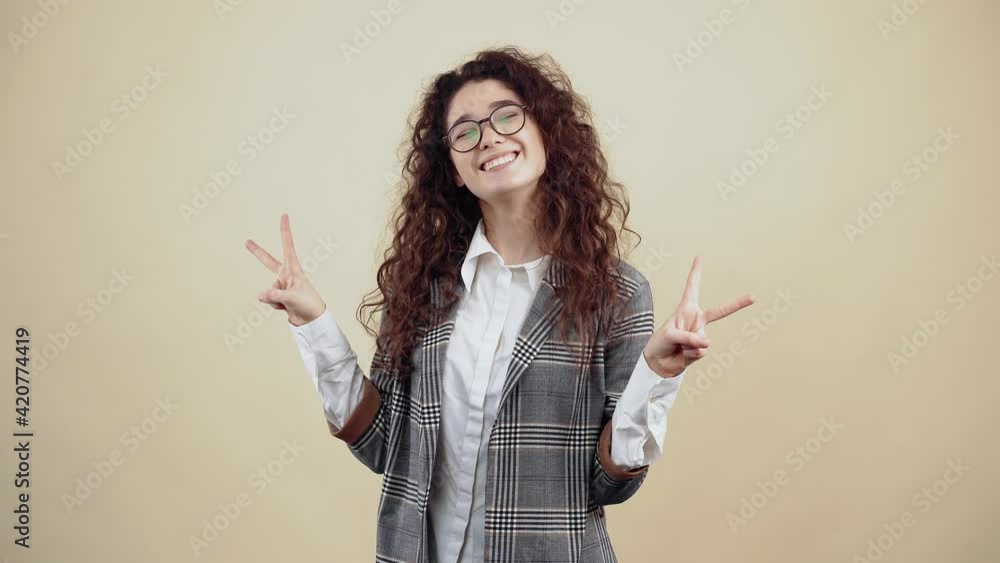 The cheerful young woman with her teeth out shows the gesture of peace ...