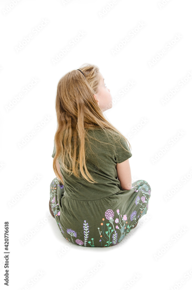 Rear view of little girl sitting on floor looking up. Isolated on white ...