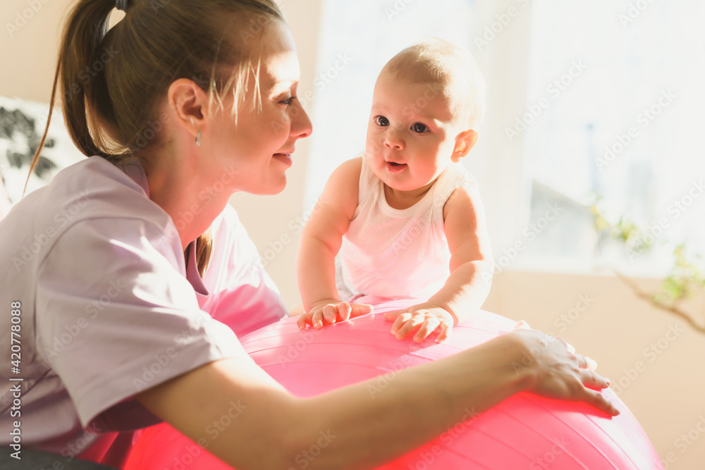 Young mother and her happy baby having fun with gymnastic ball ...
