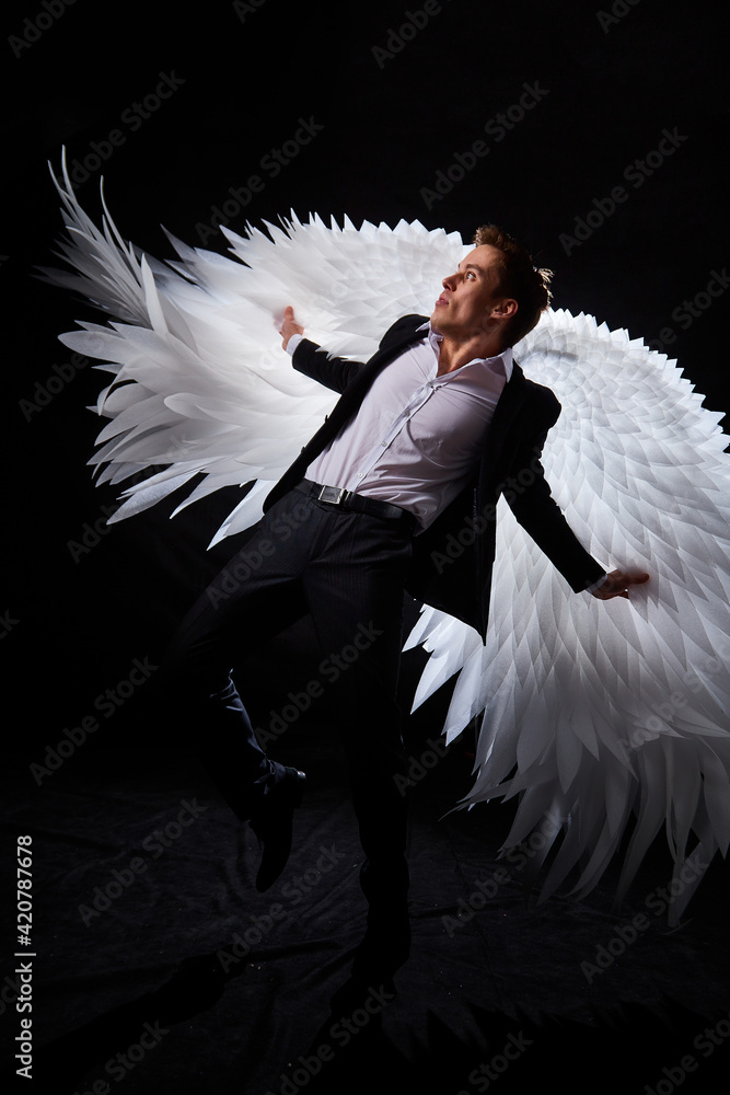 Portrait of an attractive young man in a black suit and with white ...