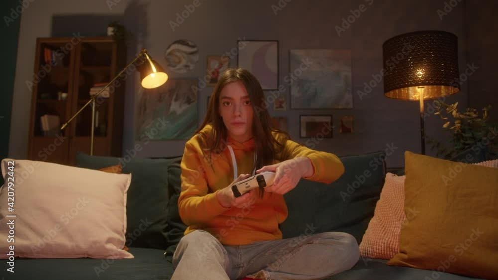 Determined girl playing a video game at living room at night. Excited ...