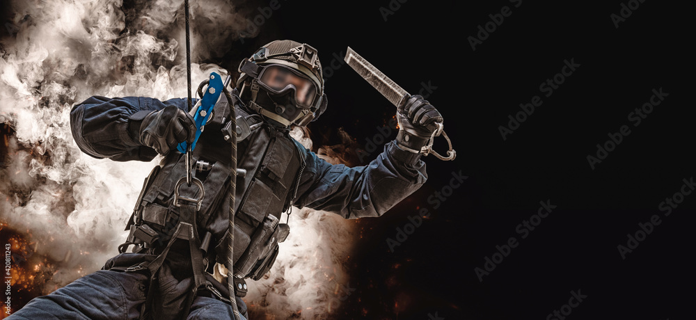 Special forces soldier hangs on a rope and swings with a special device ...