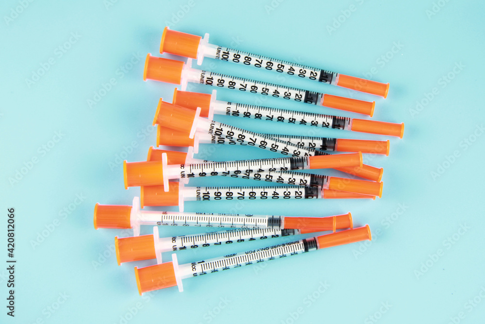 Lots of disposable insulin syringes on a blue medical background ...