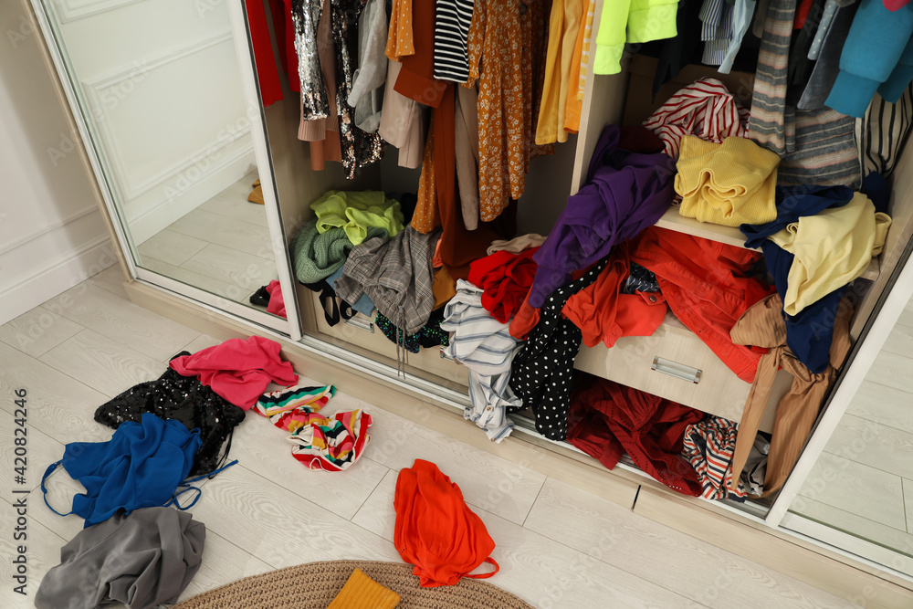 Messy wardrobe with different clothes indoors. Fast fashion concept ...