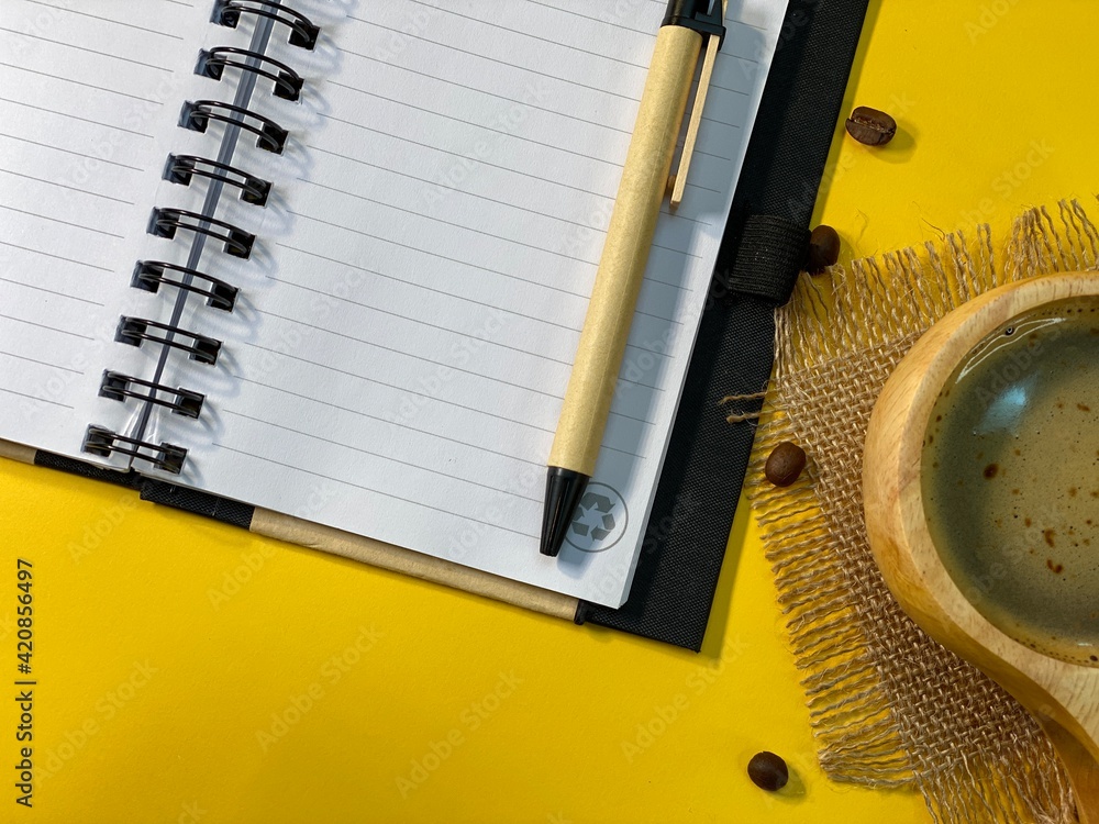 on a yellow background an open notebook with a wooden pen and next to ...