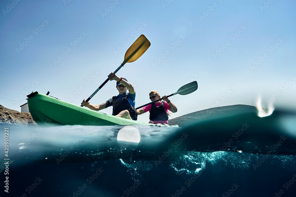 Teenage boy and mother sea kayaking on ocean, surface level view ...