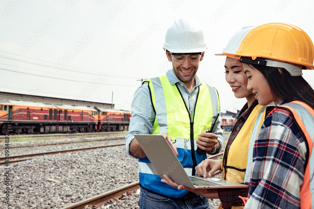 Engineers working on railway train statation and holding laptop for ...