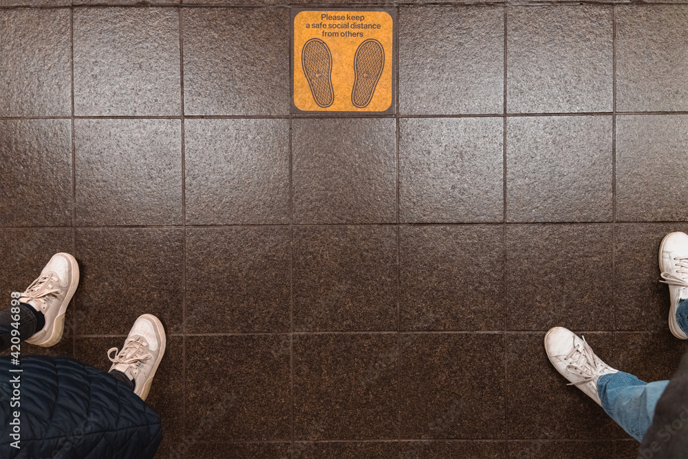 Keep social distance sign message on the ground, feet of two people ...