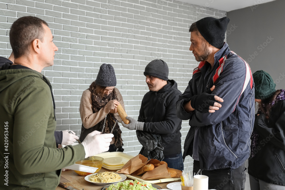 Volunteer giving food to homeless people in warming center foto de ...