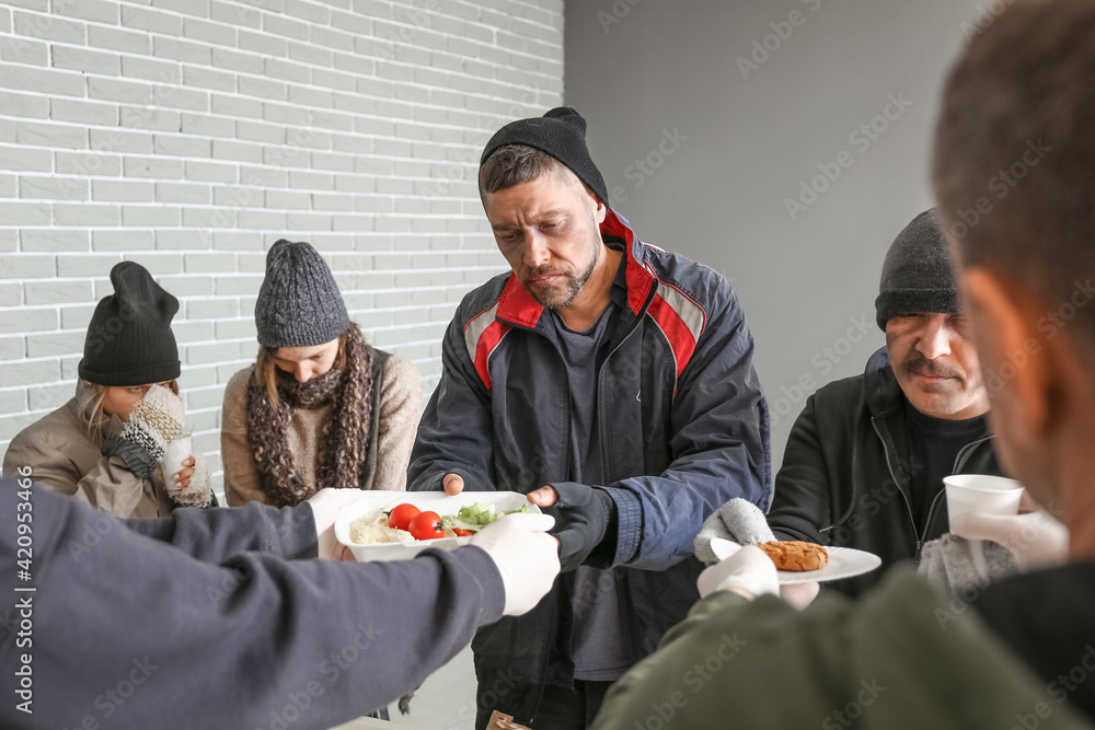 Volunteers giving food to homeless people in warming center Stock Photo ...