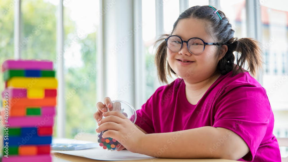 Asian girl with Down syndrome during art lesson Stock Photo | Adobe Stock