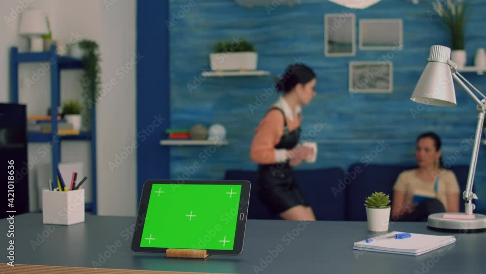 Tablet computer with mock up green screen chroma key display standing in front on office desk ...