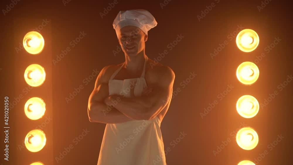 Portrait of muscular chef wearing white apron and chef hat, showing ...