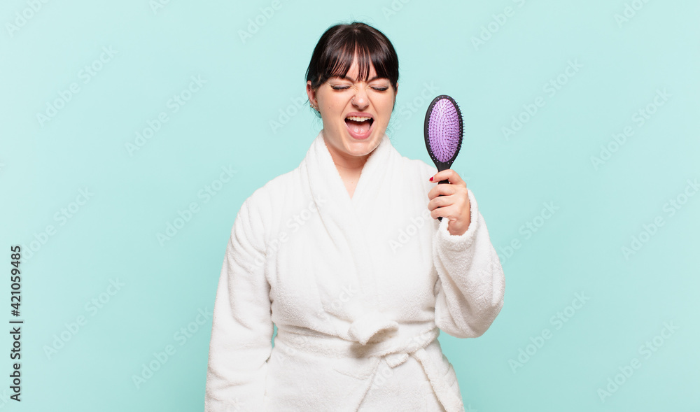 young woman wearing bathrobe shouting aggressively, looking very angry ...