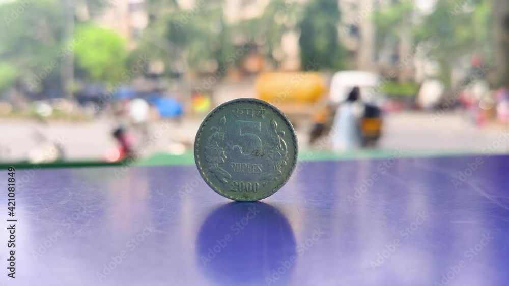 A Five rupees Indian Currency coin kept on table with Indian street ...