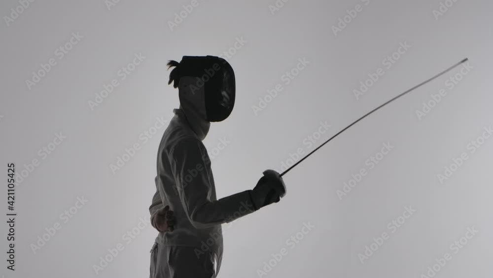 Side view portrait of young guy with rapier in his hands on gray studio ...