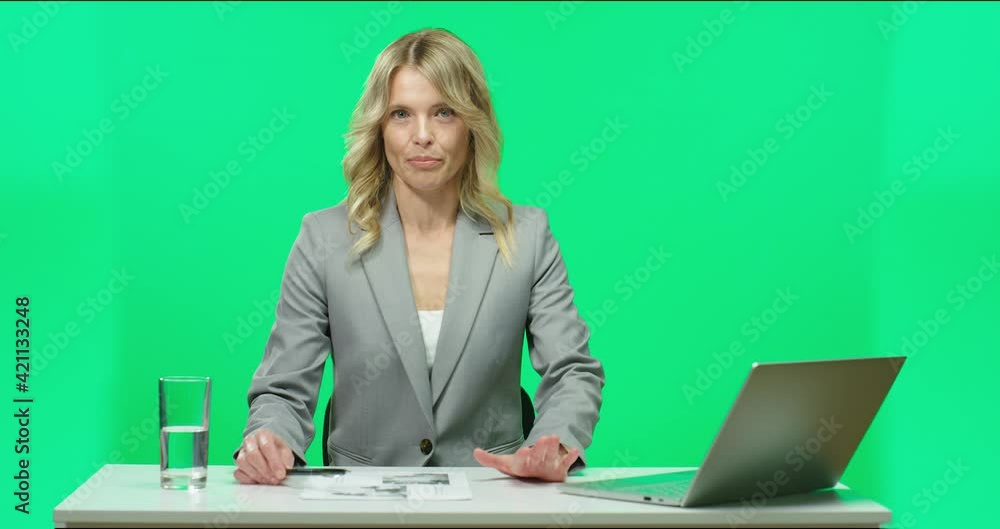 Popular female TV presenter in gray suit sitting in studio at table ...