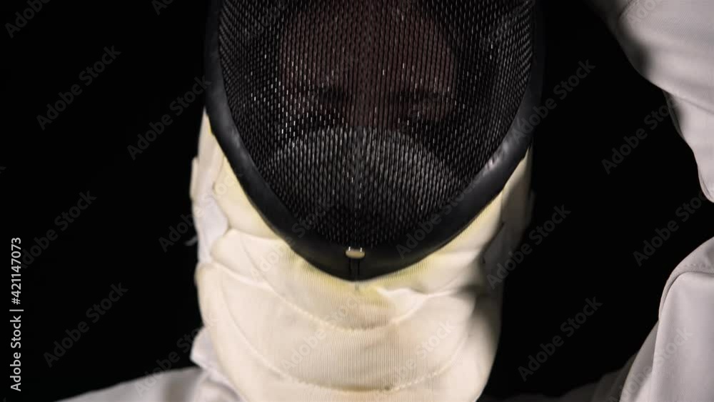 Portrait of a confident fencer looking at the camera and putting on a ...