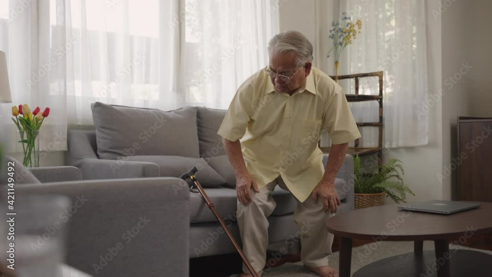 Asian old man hold wooden walking stick sit on couch in living room ...