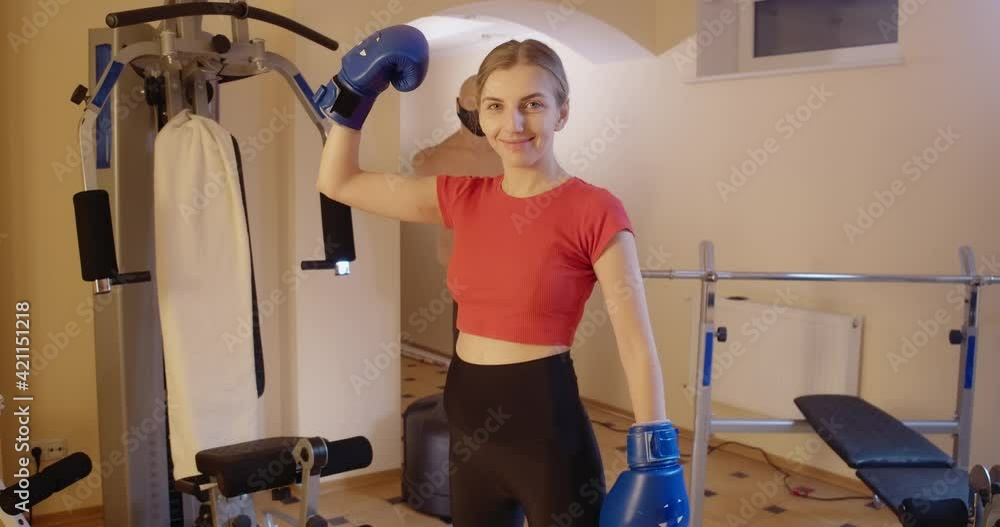 Portrait of confident female boxer looking at camera showing strength ...