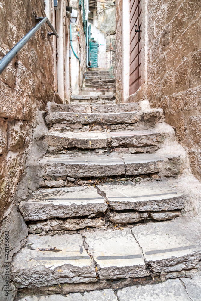 Ancient stone steps leading steeply up an old narrow alleyway in Kotor ...