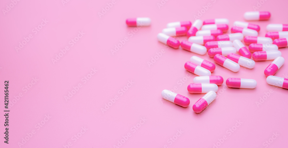 Pink-white antibiotic capsules pill spread on pink background with ...