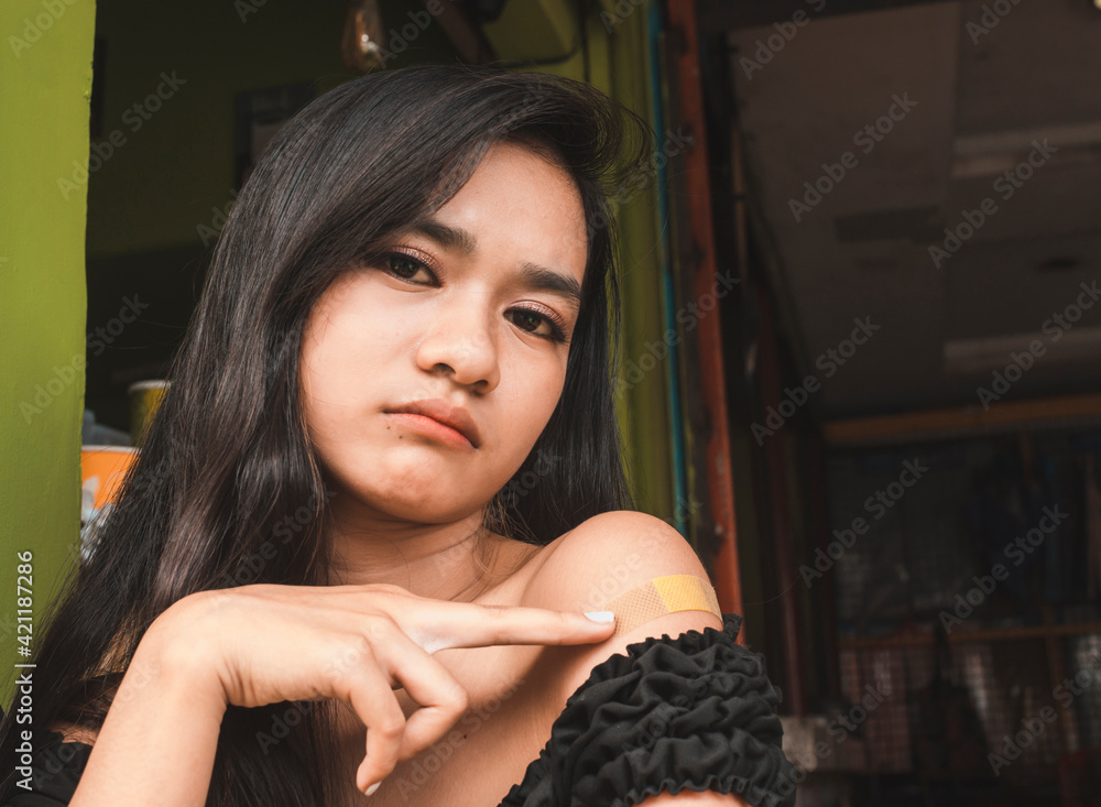 A pretty asian girl gives a flirty pout over a small cut or wound ...