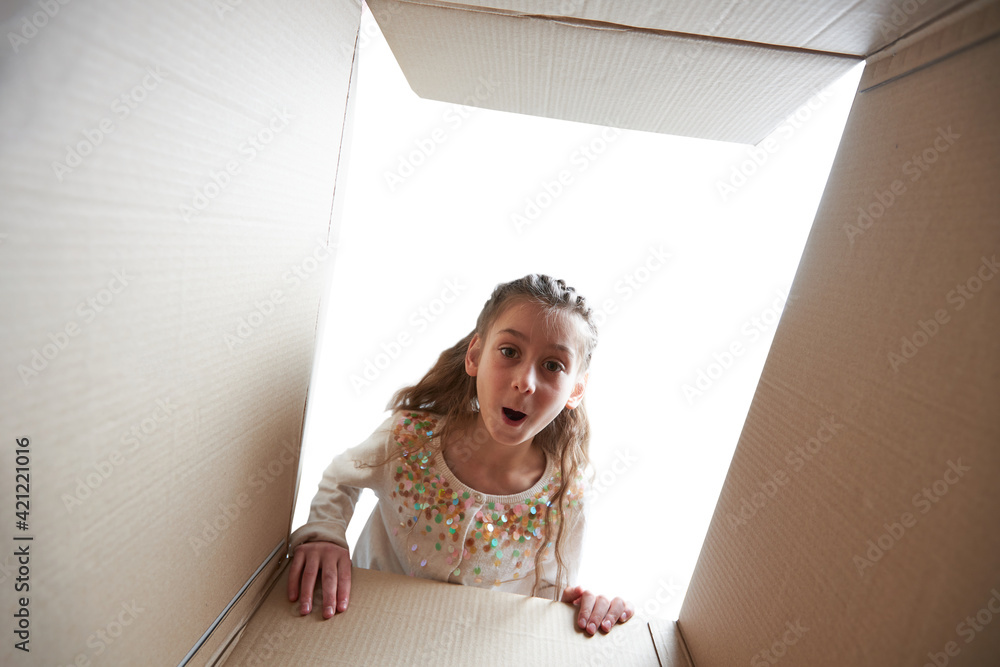 Child girl looking into a box with a present. She is happy and smiling ...
