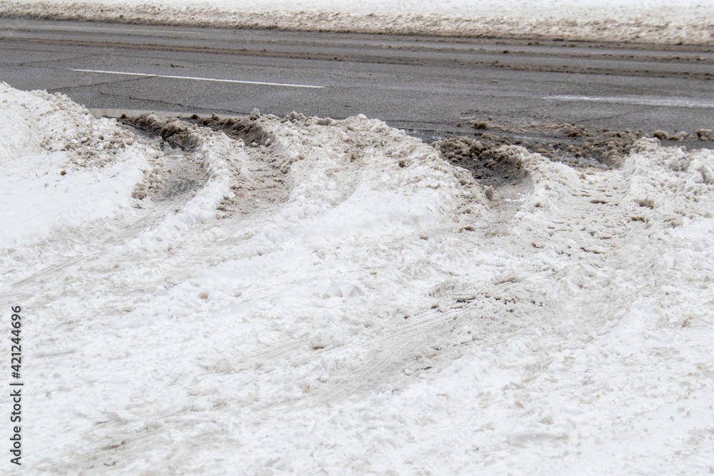 Slippery slushy snow with tire marks and ruts at road entrance to ...