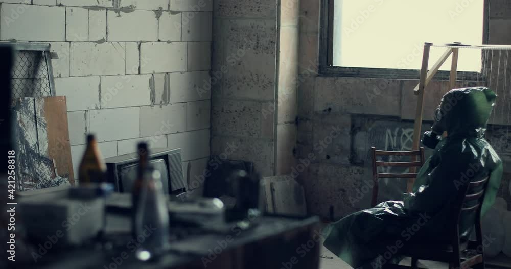 in the middle of the destroyed room man sits in a gas mask and does not ...