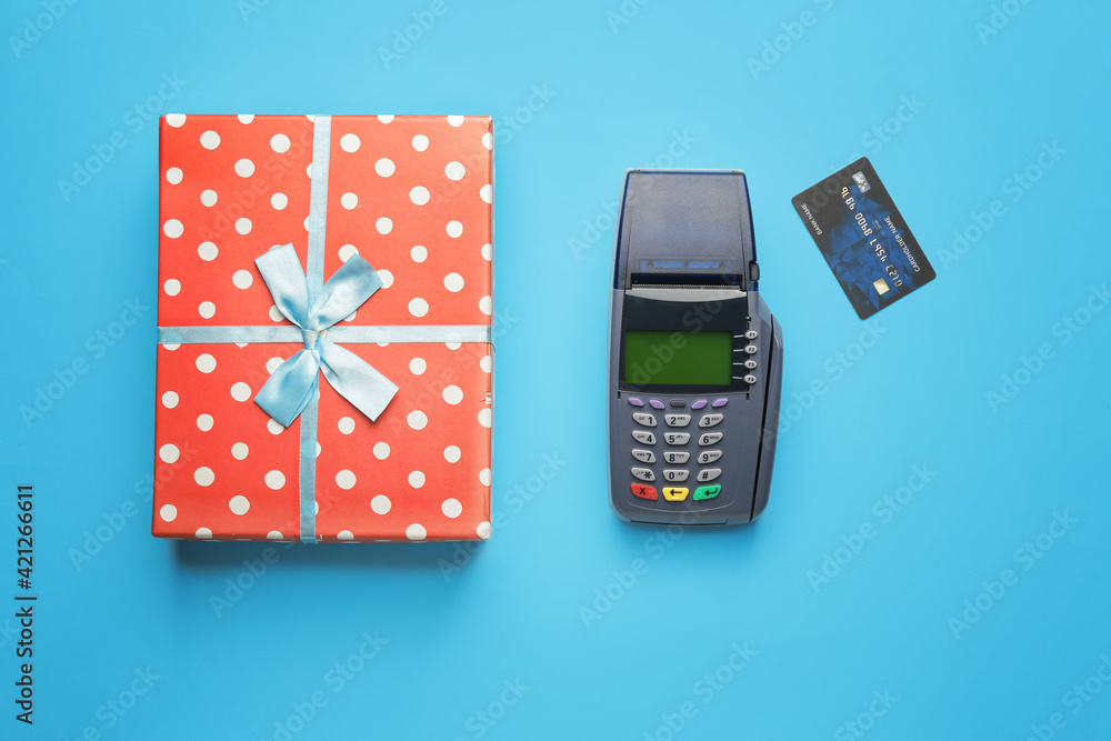 Payment terminal with credit card and gift box on color background ...