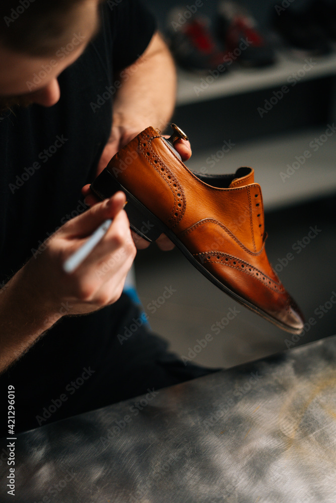 Top view of shoemaker painting heel and sole of light brown leather ...