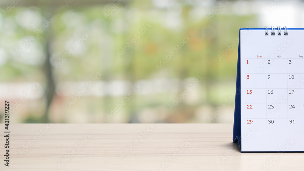 white paper desk calendar on wood table with blurred bokeh background ...