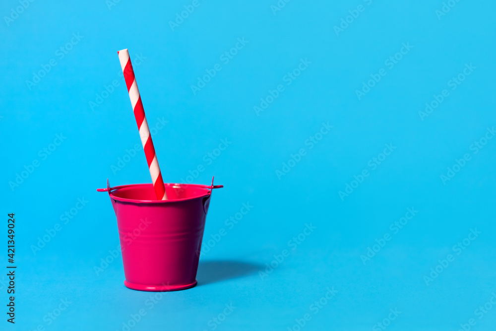 One pink and red toy bucket on a light blue background with a striped ...