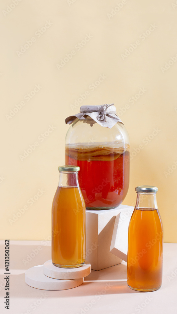 Glass gar with komucha tea and two bottles with ready beverage on ...