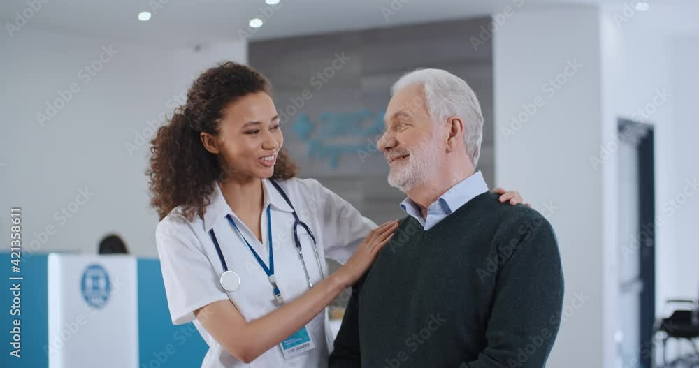 Vidéo Stock Cute female multiethnic doctor hugs shoulders senior male ...