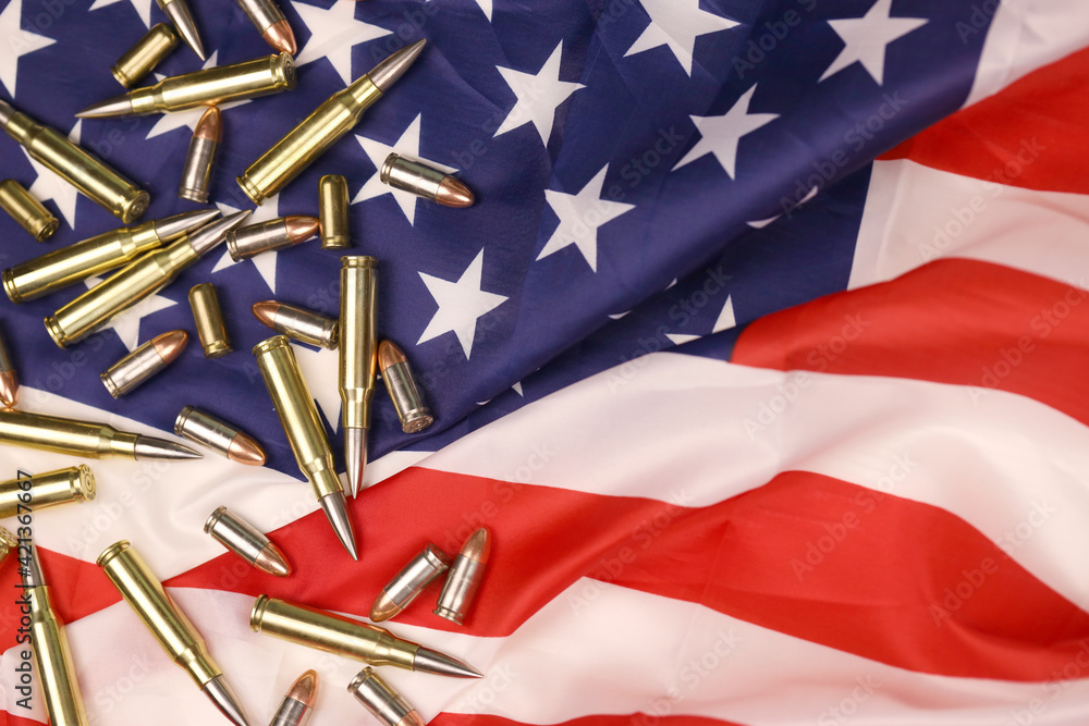 Many yellow 9mm and 5.56mm bullets and cartridges on United States flag ...