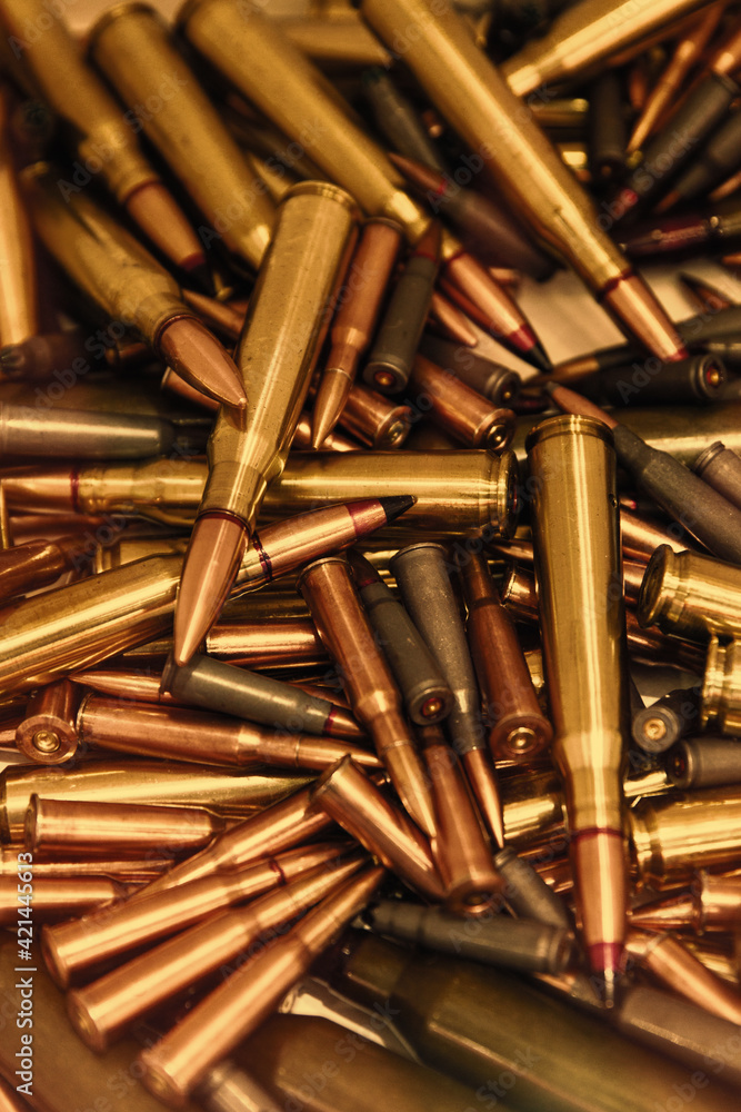 Pile of bullets with copper tips under a warm light. Close up of a lot ...