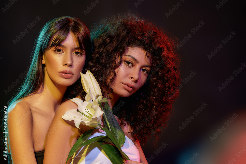 Two young women with different hair types and perfect makeup looking at ...