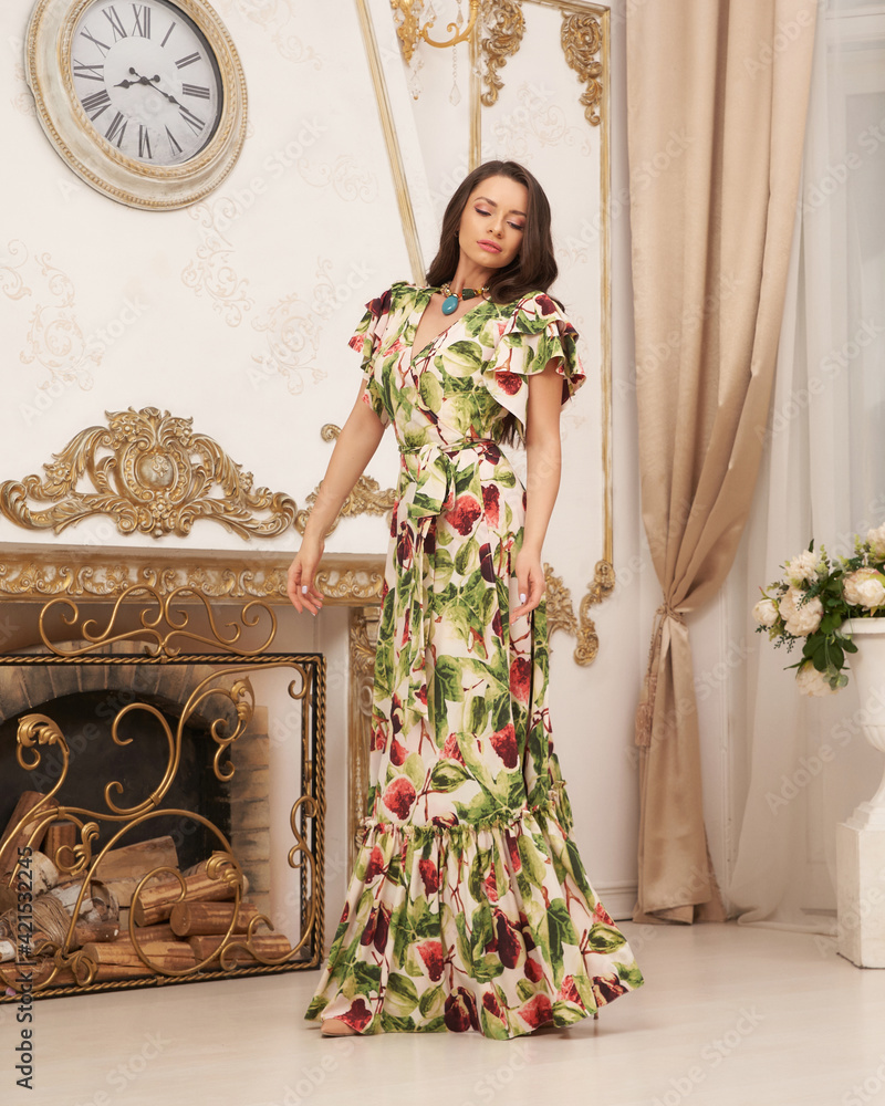 Elegant lady in green sundress with floral design standing and posing ...