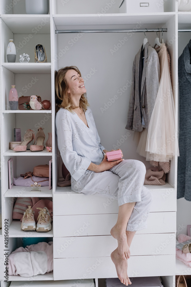 Young woman sits in a modern dressing room with a gift box. Girl dreams ...
