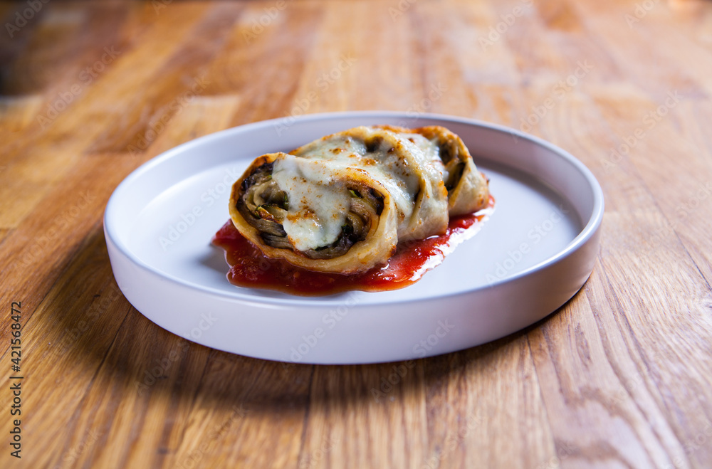 Roulade with eggplant, onion and basil in tomato sauce covered with ...