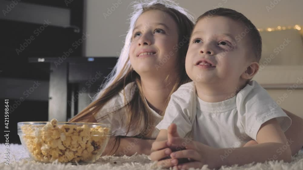 Happy family, brother and sister watching tv with popcorn bowl at home ...