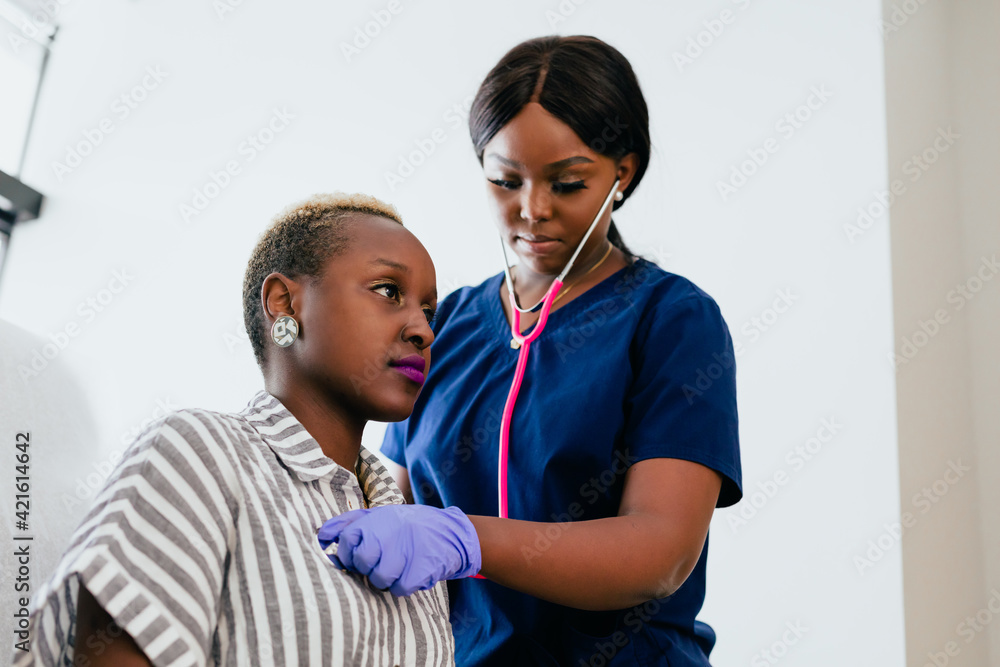 Black nurse listening to heart and breathing of woman patient 스톡 사진 ...