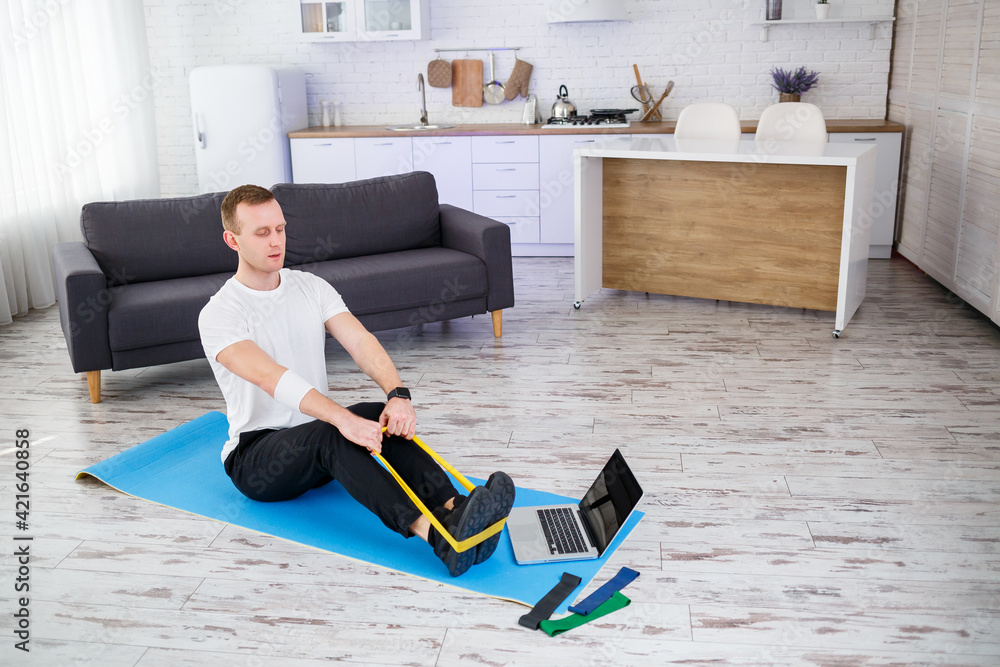 Online training. Young man doing exercise with fitness rubber bands ...