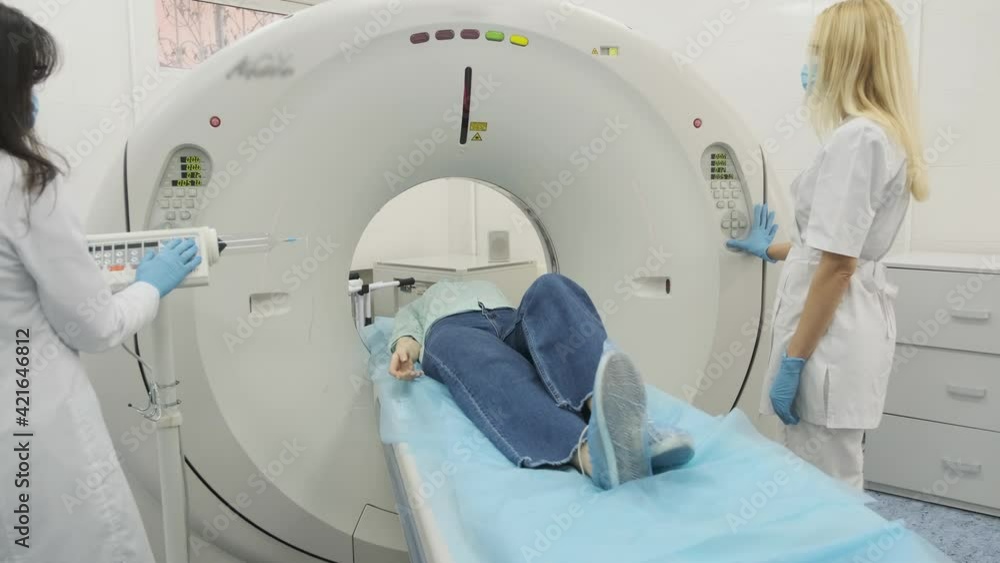 Female patient is undergoing CT or MRI scan under supervision of two ...